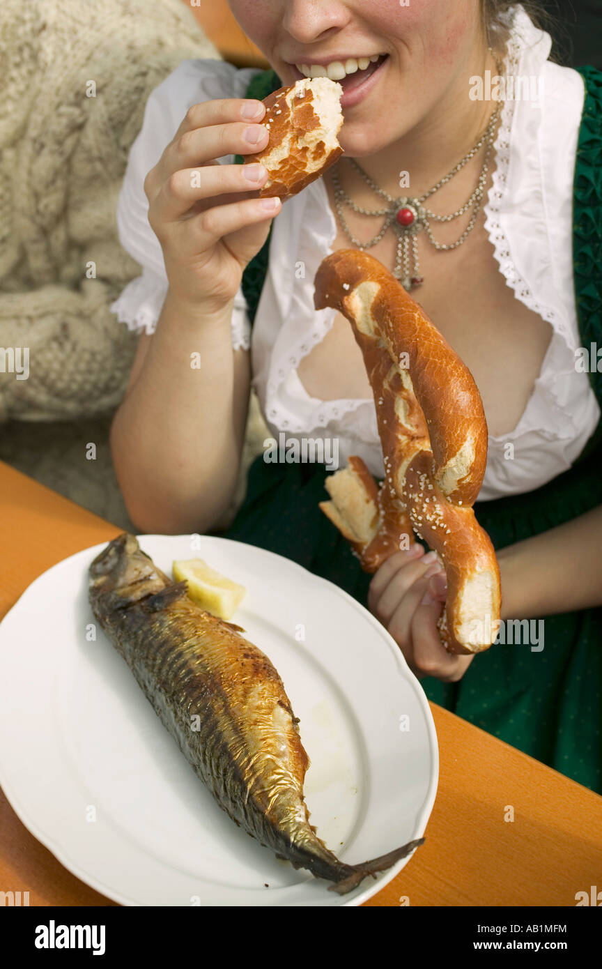 Woman eating pretzel Steckerlfisch skewered fish Oktoberfest ...