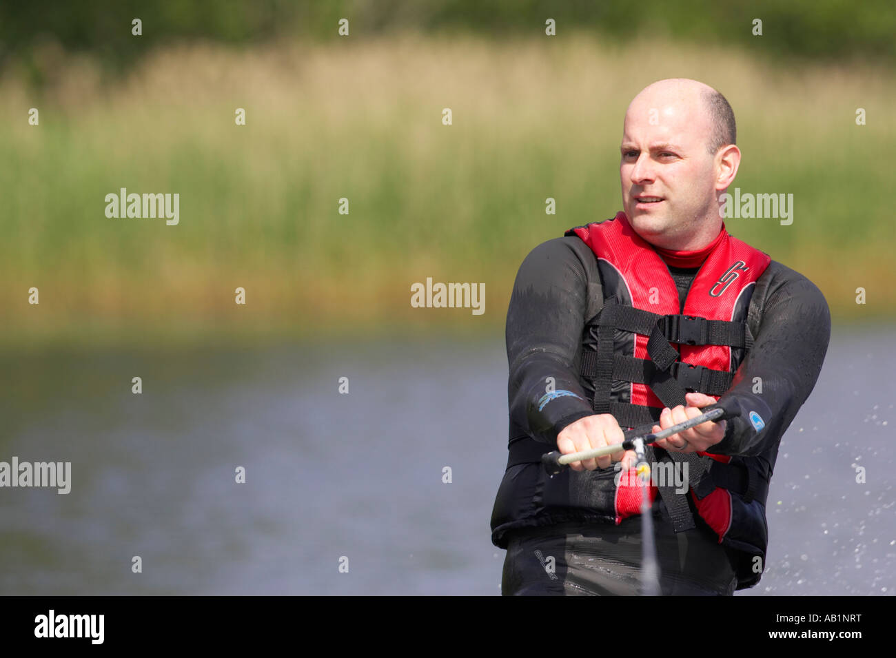 mid 30s male in red and black wetsuit and flotation aid looks around ...