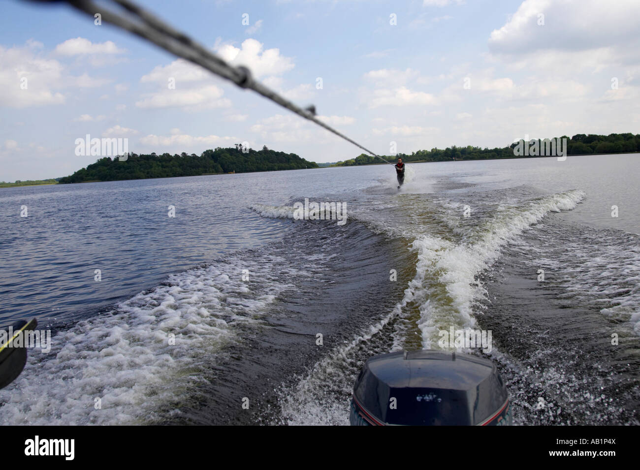 slanted male waterskier being towed at the end of tow rope in the wake ...