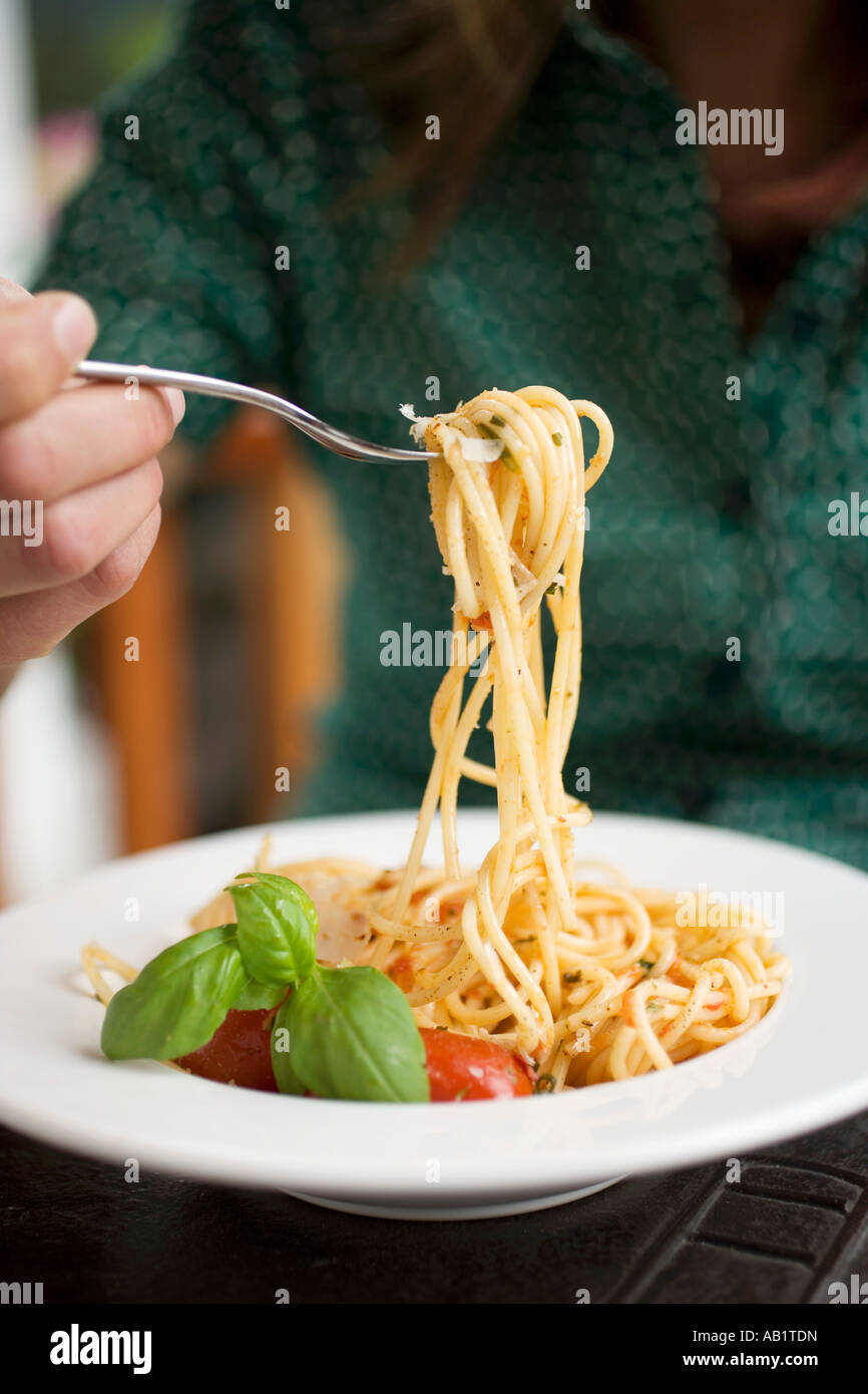 Woman eating spaghetti with tomatoes and basil FoodCollection Stock ...