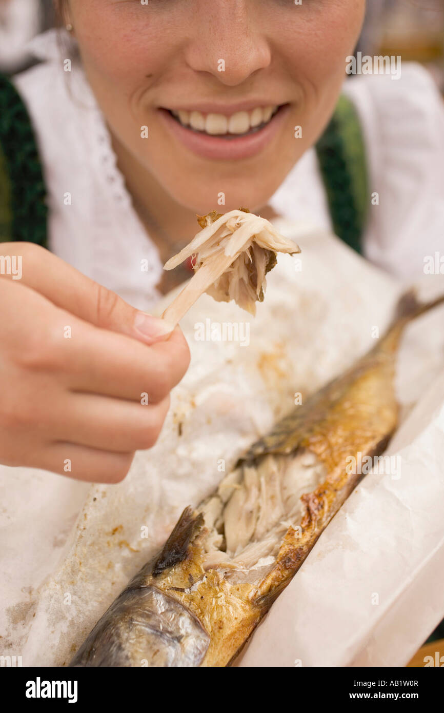 Woman eating Steckerlfisch fish on stick Oktoberfest Munich ...
