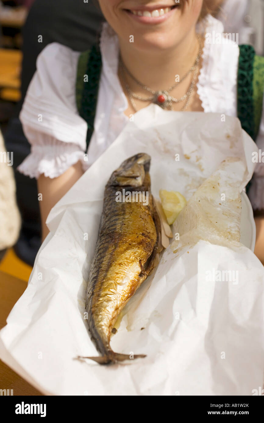 Woman holding Steckerlfisch fish on stick Oktoberfest Munich ...