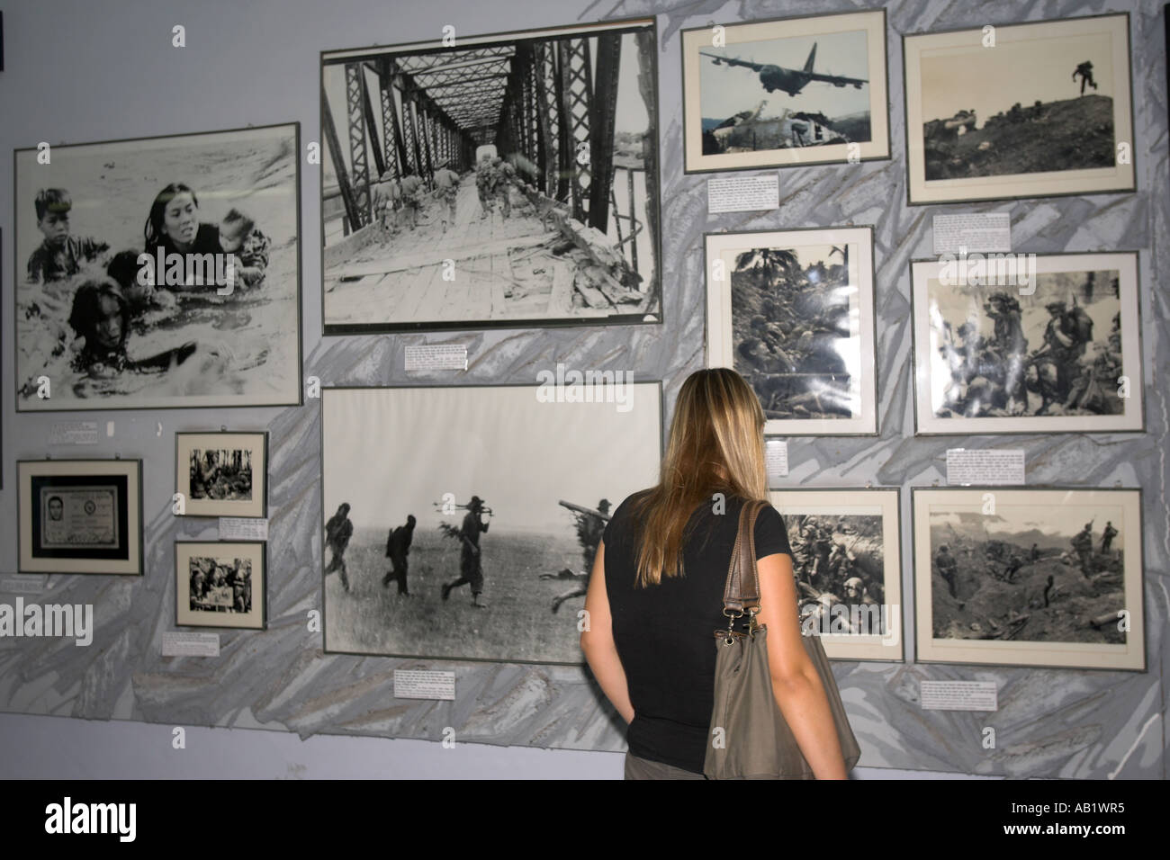 Woman studies Vietnam War photographs in gallery War Remnants Museum Ho ...