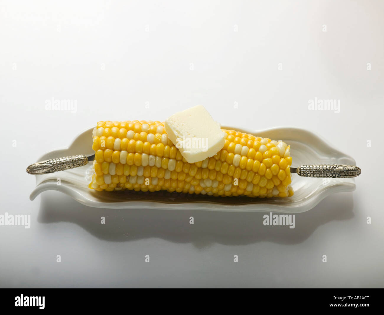 Corn cob with knob of butter in white dish FoodCollection Stock Photo ...