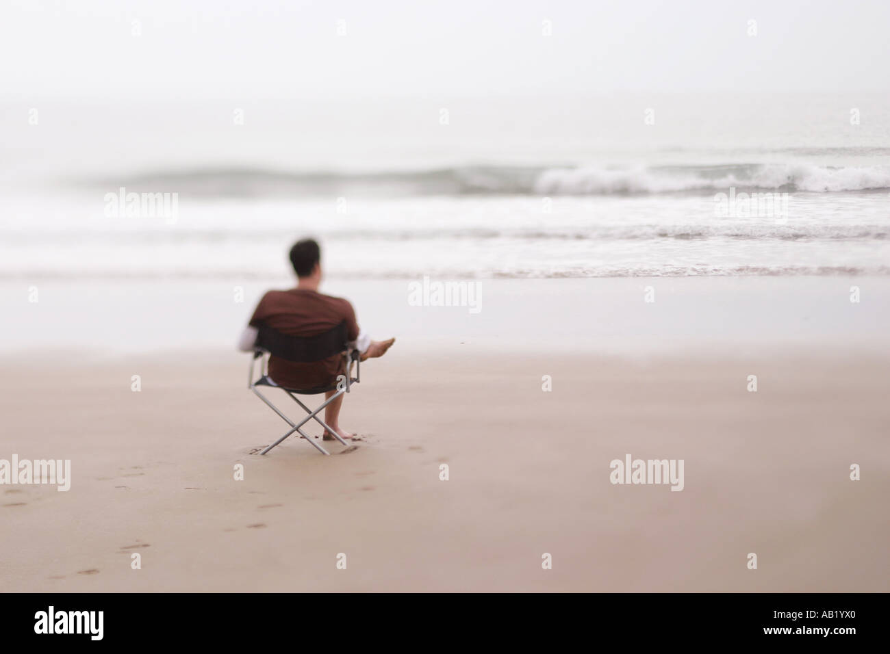 man sitting in a chair by the sea Stock Photo - Alamy