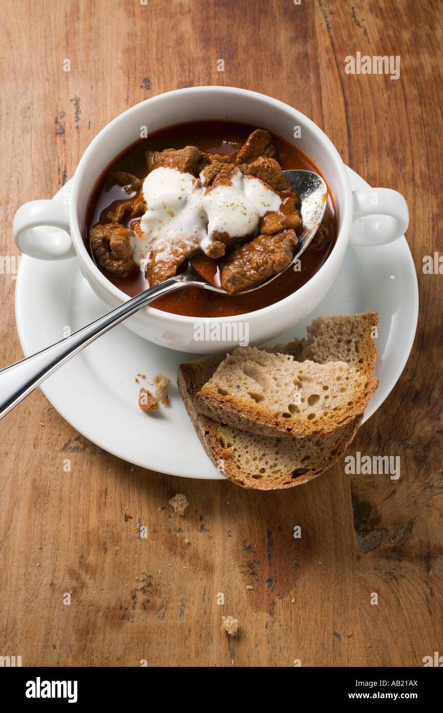 Goulash soup with sour cream in soup cup slices of bread FoodCollection ...