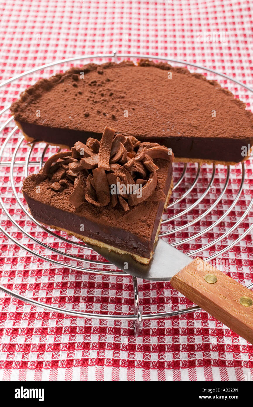 Chocolate tart on cake rack and piece on cake server FoodCollection ...