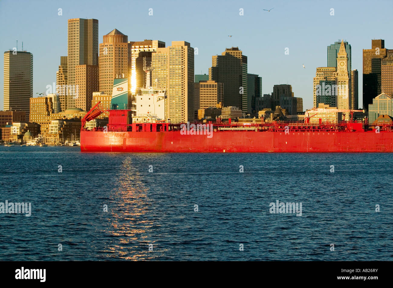 Bright red cargo ship travels in front of Boston Harbor and the Boston ...