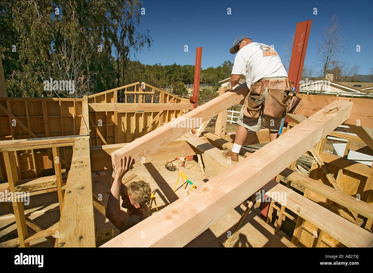 Workers position support beams into framing of house in Southern ...