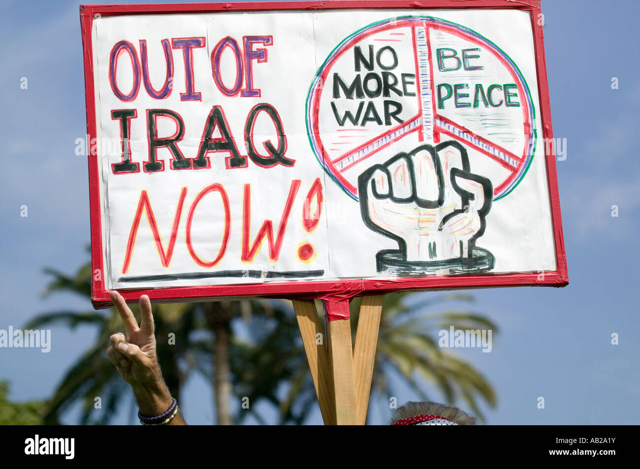 A man gives the peace sign and holds a sign saying Out of Iraq Now at ...