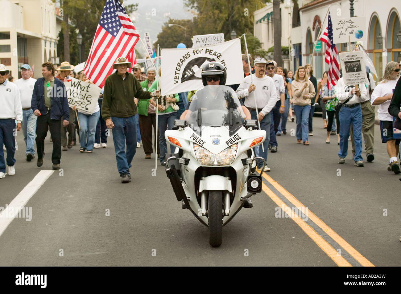A motorcycle policeman leads parade of protesters against George W Bush ...