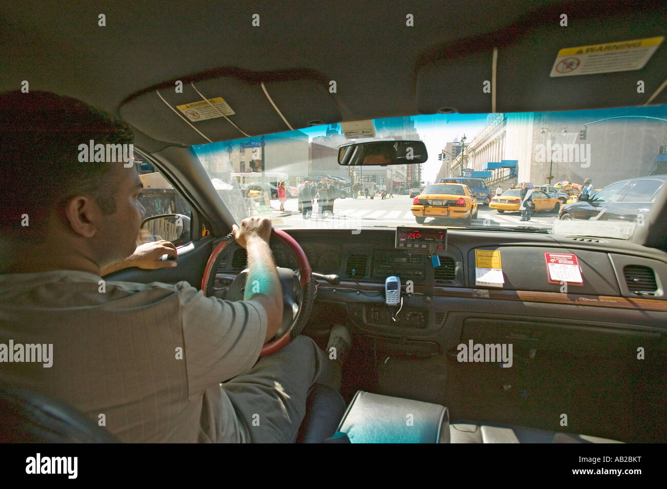 Interior view of taxi cab and driver steering through New York City ...