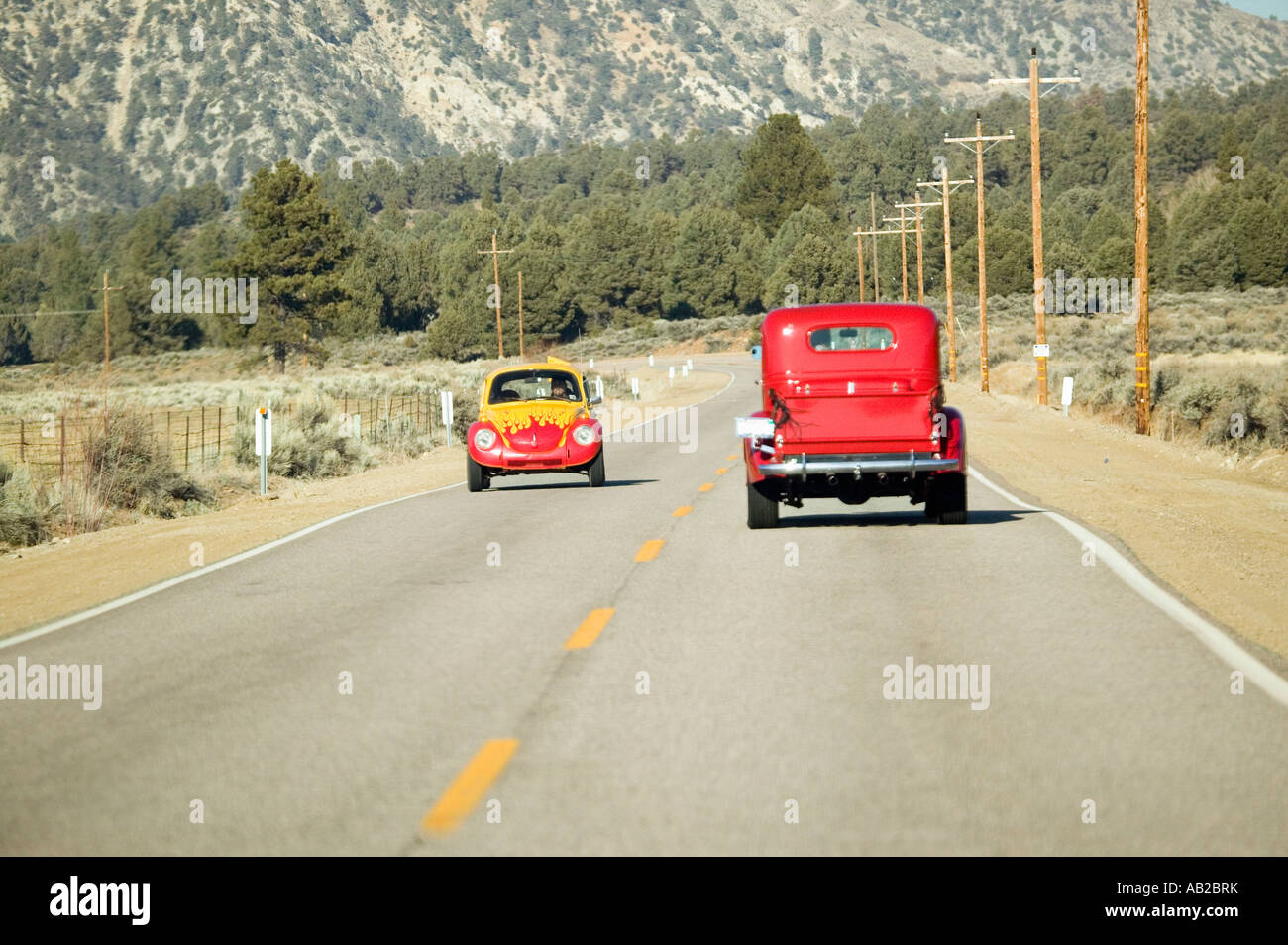 A yellow and red VW hotrod drives in opposite direction of a restored ...