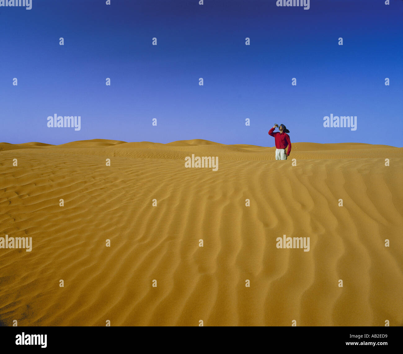 Man in sand desert drinking from a bottle Stock Photo - Alamy