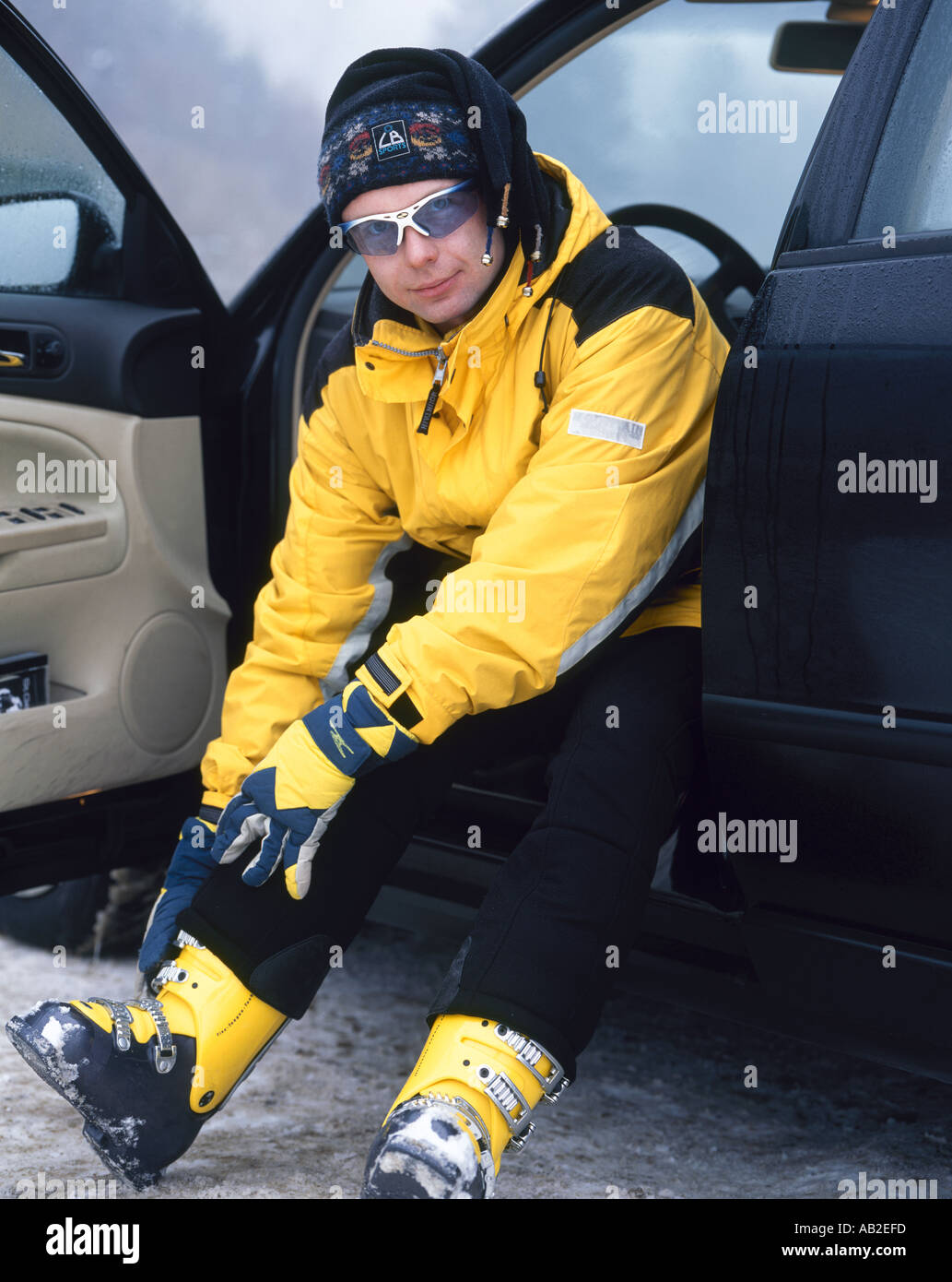 Man sitting in a car and putting on ski gear Stock Photo - Alamy