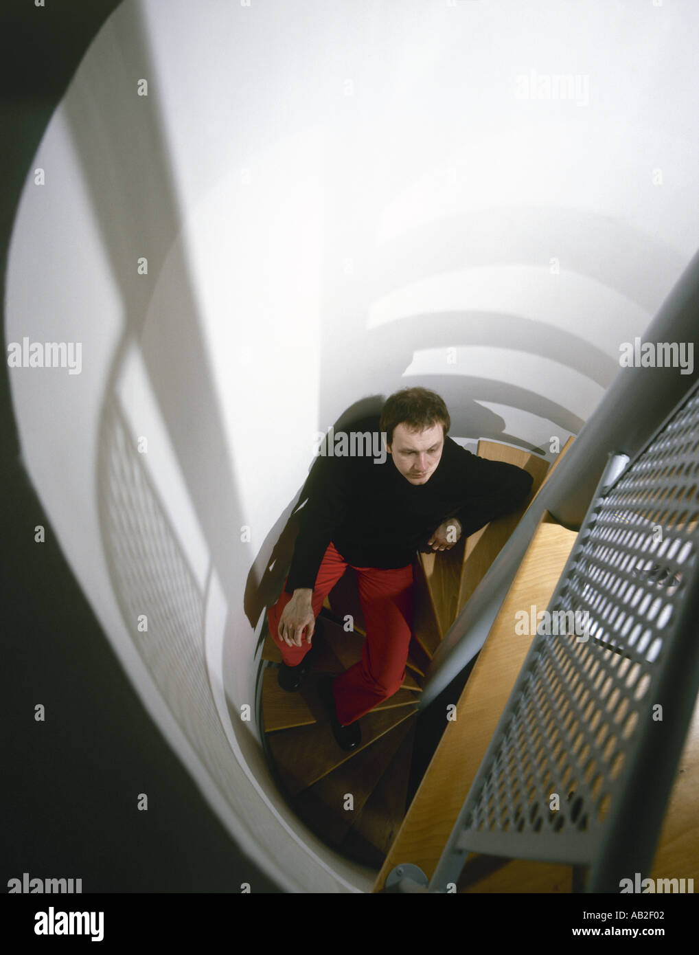 Man sitting on a spiral staircase Stock Photo - Alamy