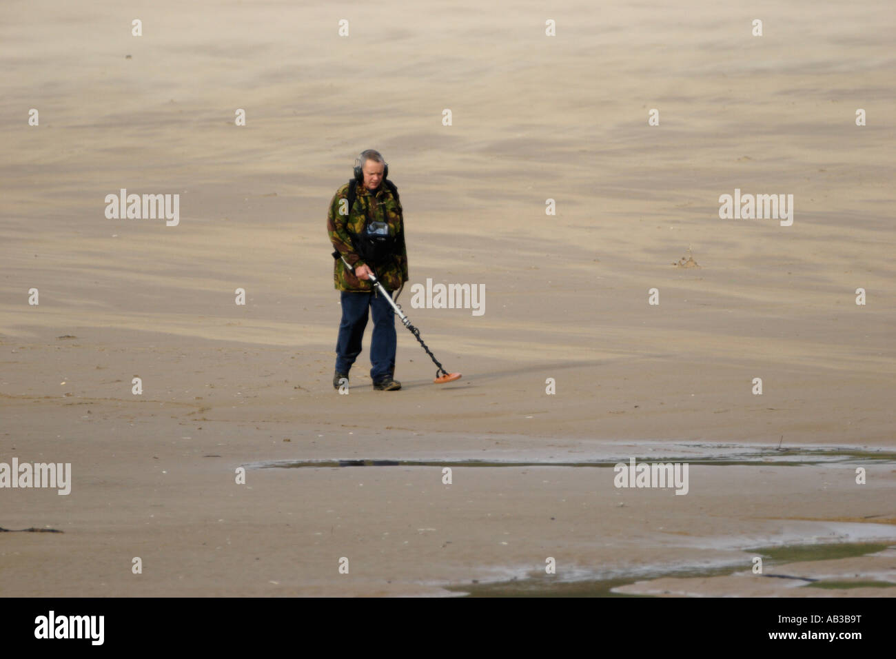 MAN USING A METAL DETECTOR ON A SANDY BEACH Stock Photo - Alamy