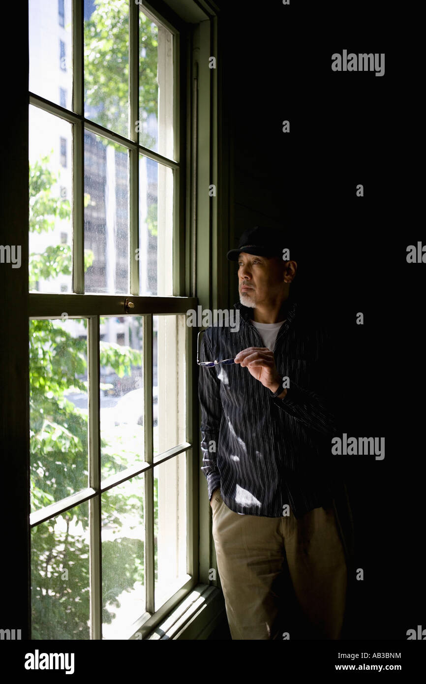 Senior man standing by window Stock Photo - Alamy