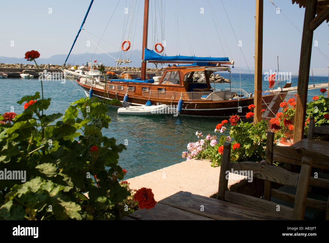 Sailboat in Assos harbor with dockside restaurant at Behramkale, Turkey ...