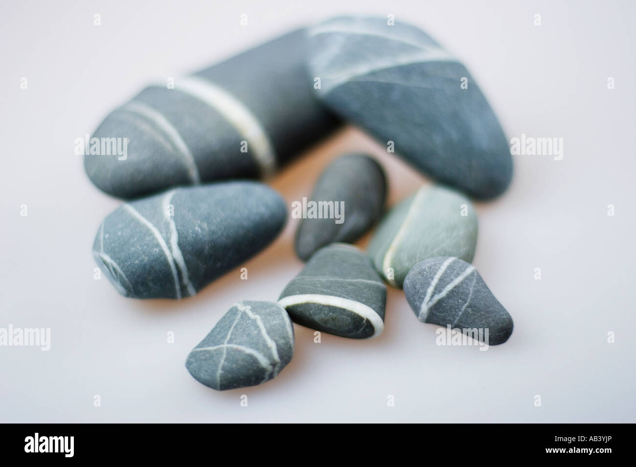 Multiple grey beach pebbles against a plain background Stock Photo - Alamy