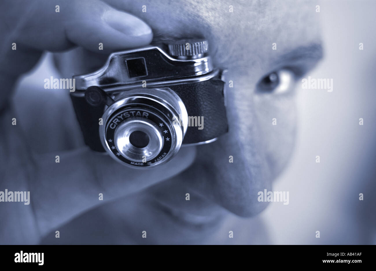 Humorous male face looking through tiny camera smiling Stock Photo - Alamy