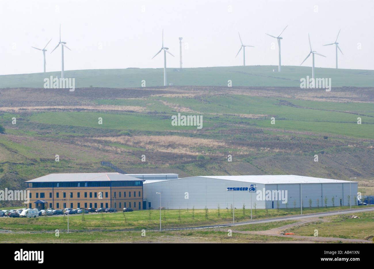 Wind turbines on hilltop with modern factory below at Gilfach Goch ...