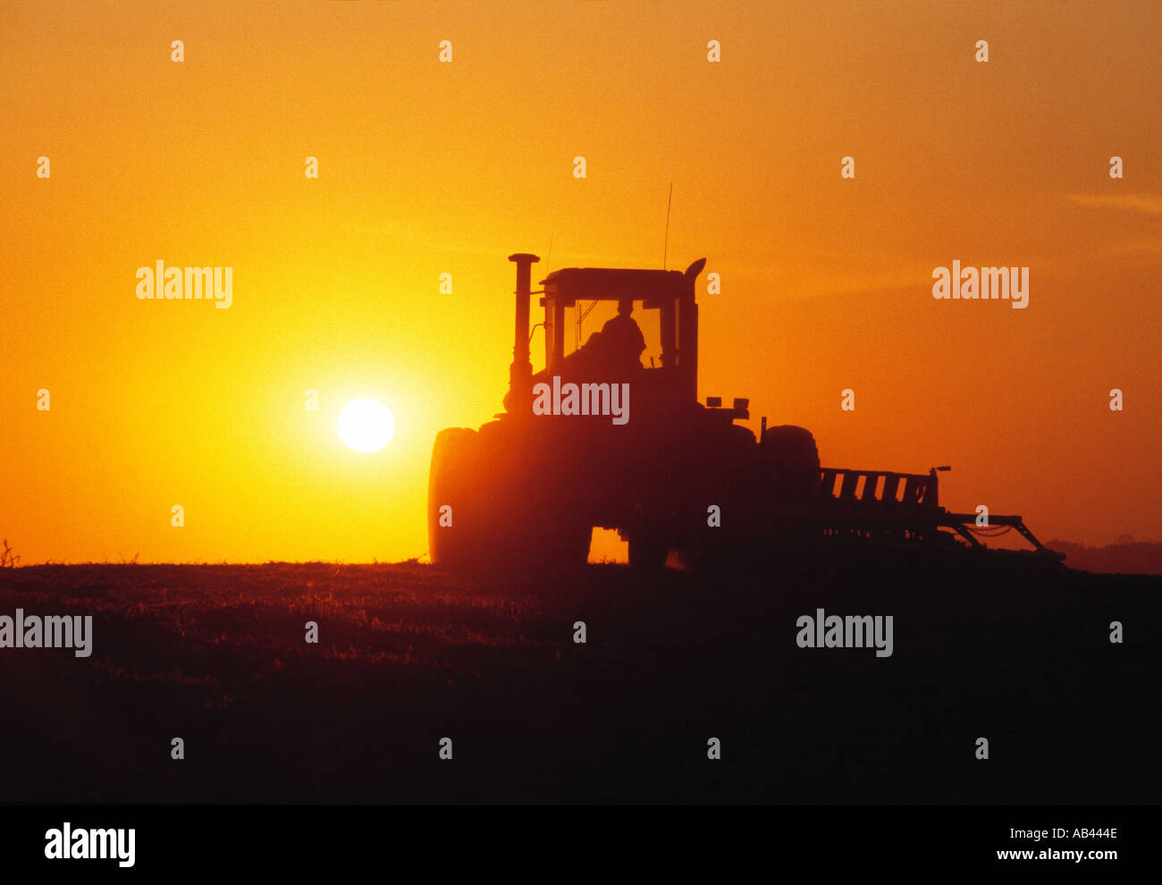 Agriculture - A large tractor pulling a tillage implement prepares a ...