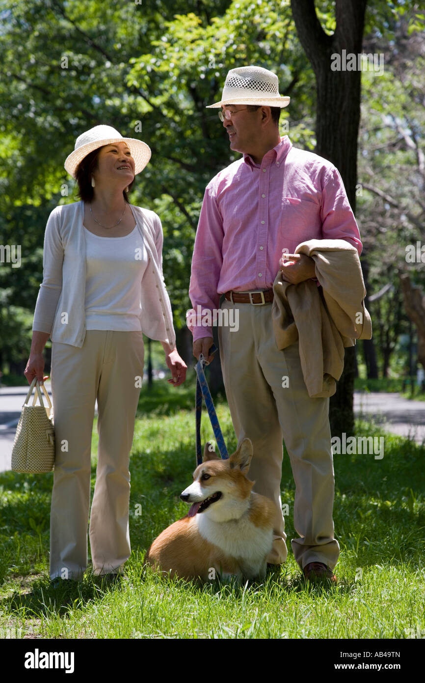 Mature couple walking with dog Stock Photo - Alamy