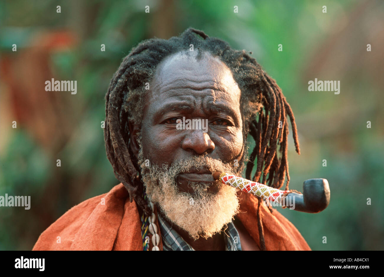 Portrait shot of a colourful tribal elder smoking an elaborate pipe ...