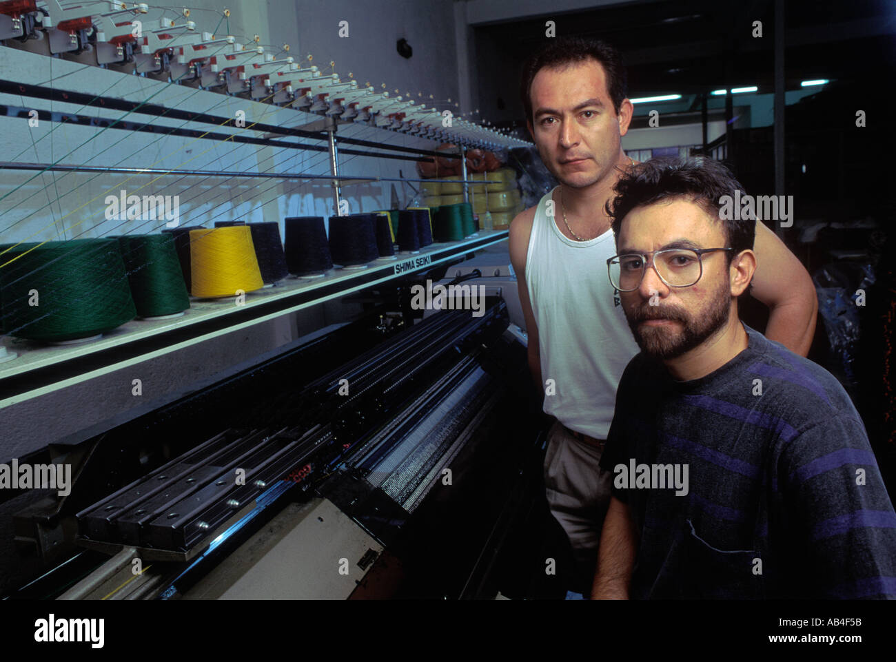 Sweater manufacturing factory owners by a mechanical loom in the plant ...