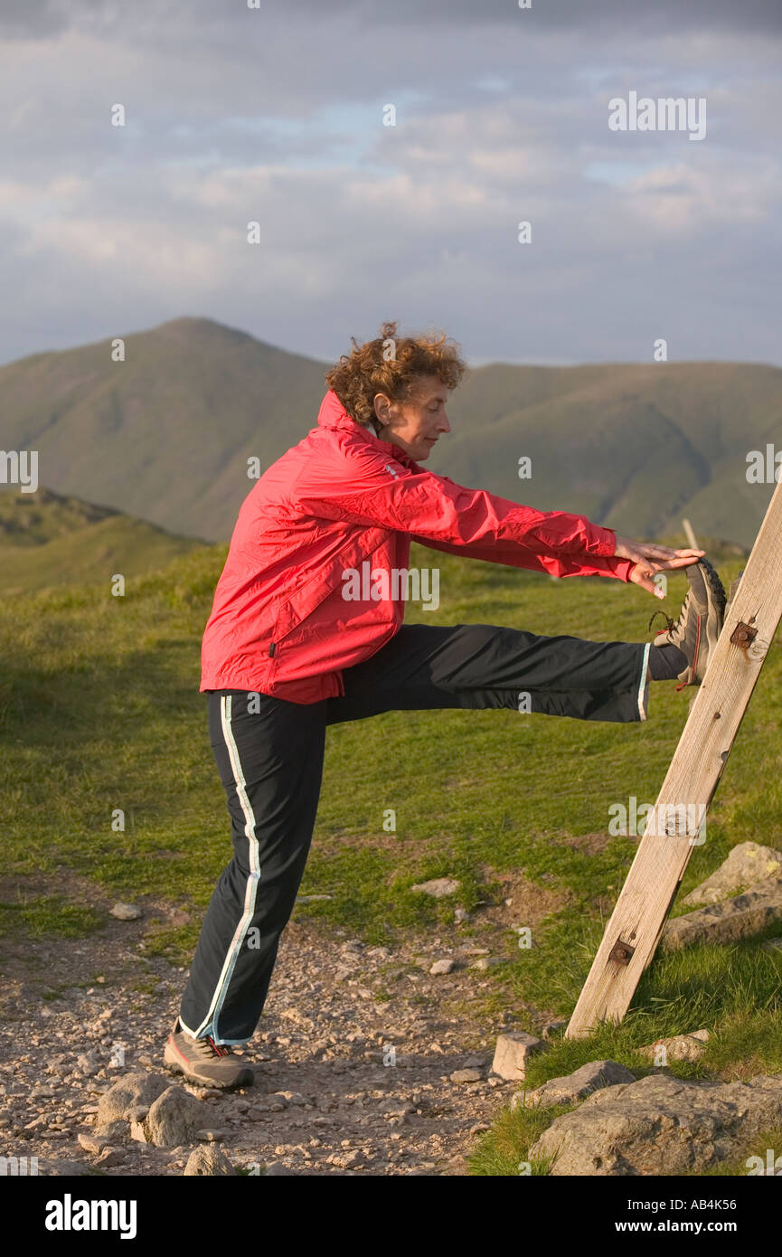 Fell runner stretching after a fell run on the summit of wansfell above ...