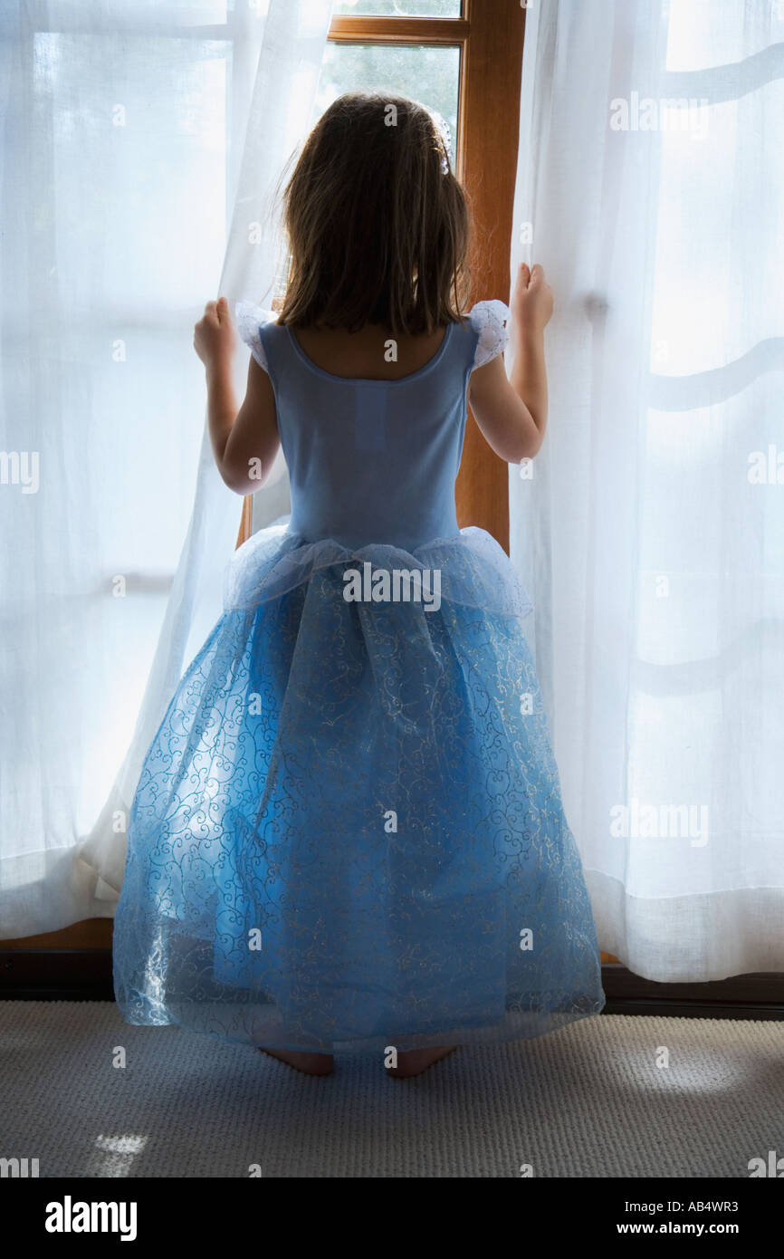 Rear view of girl dressed as princess and looking out window Stock ...