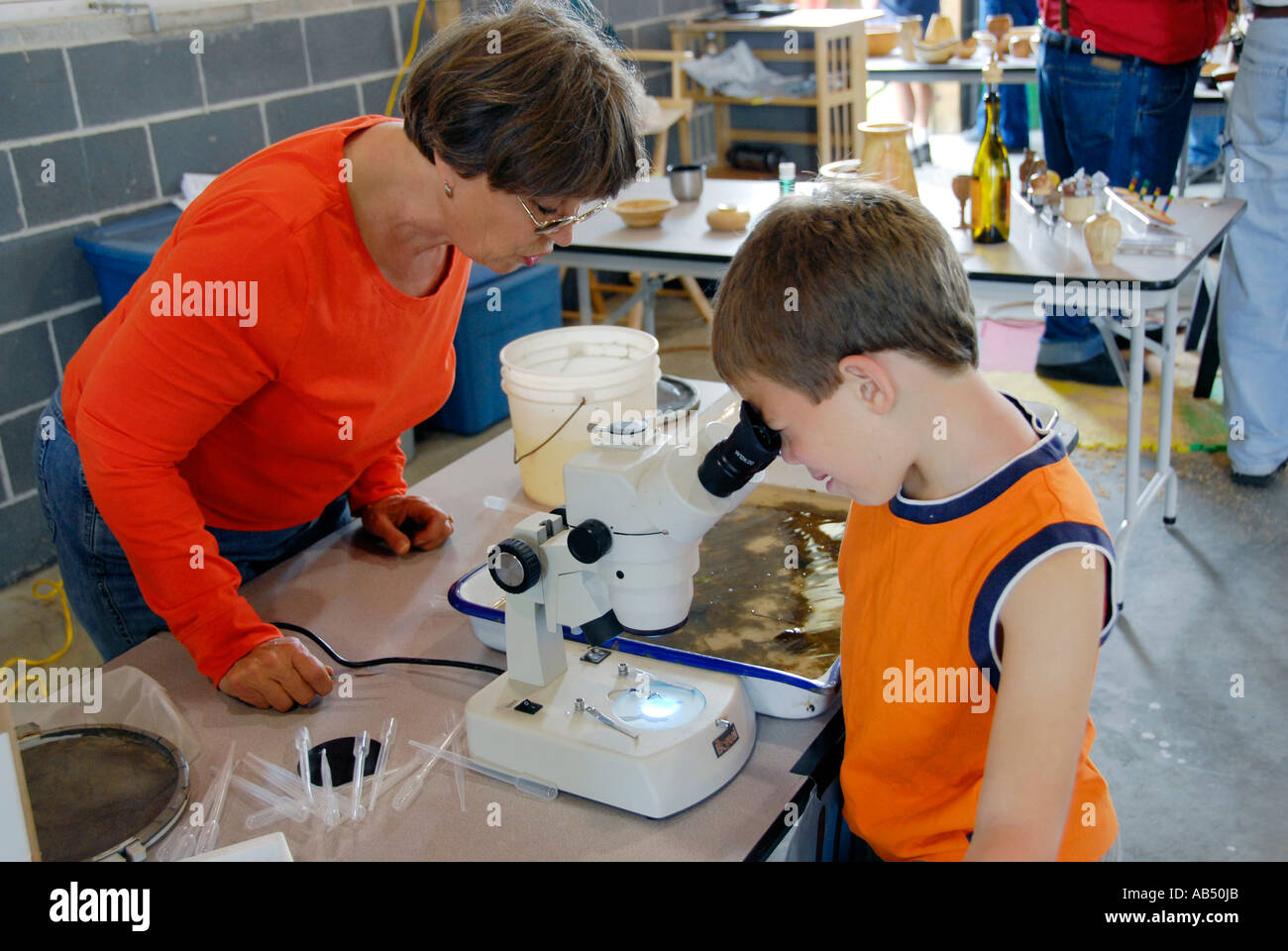 Children look through a microscope at the life in a pond at an Earth ...