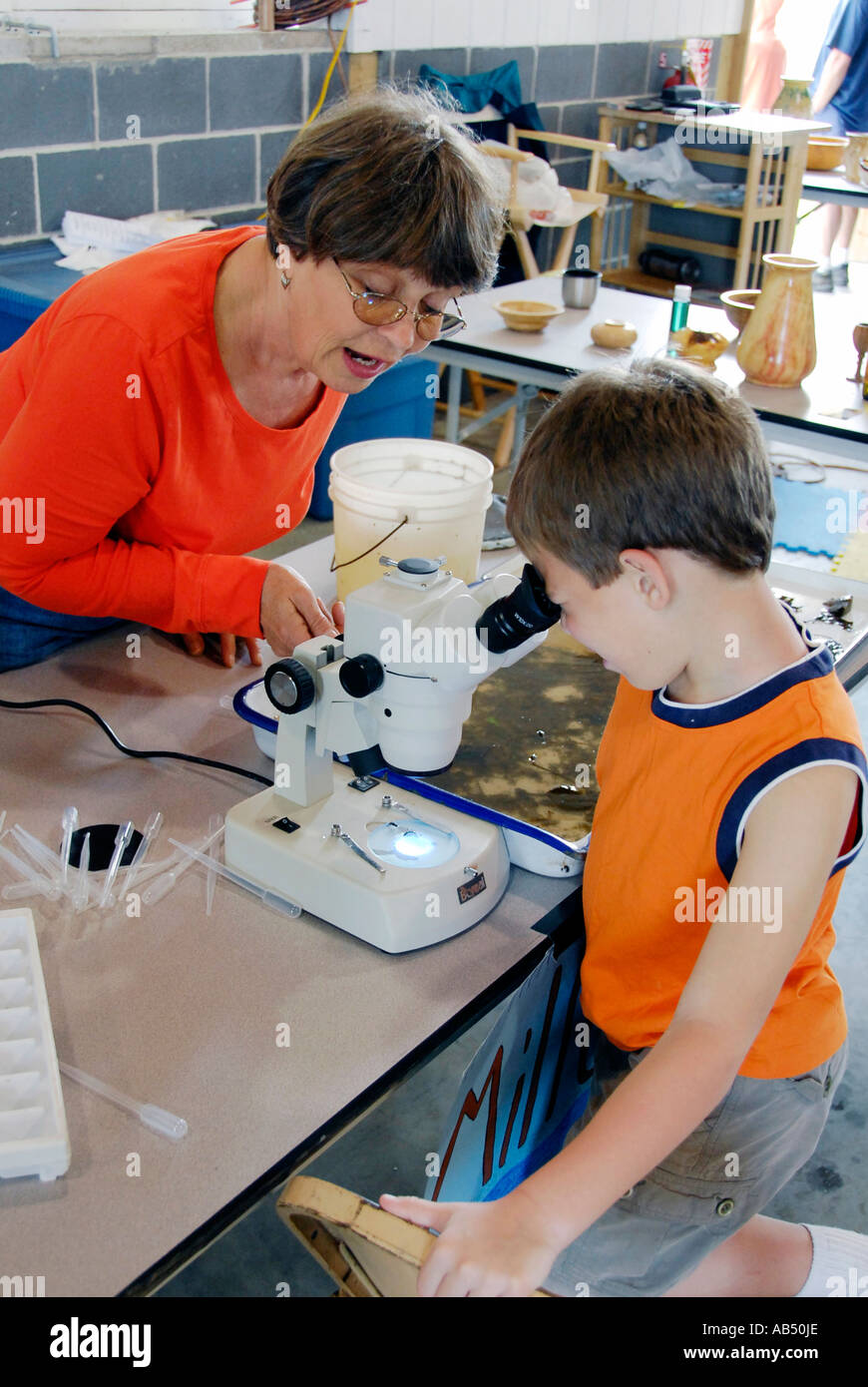 Children look through a microscope at the life in a pond at an Earth ...