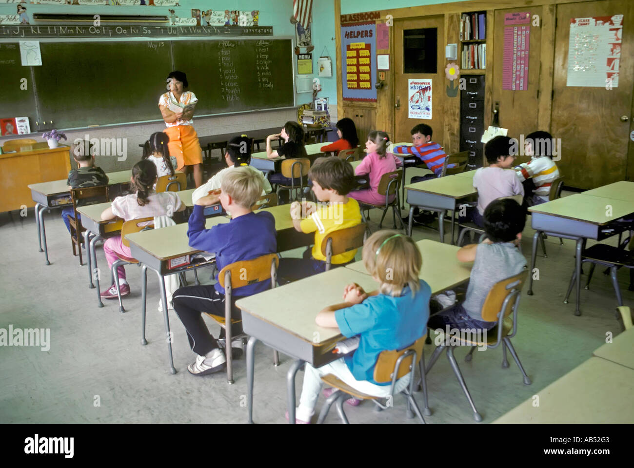 Third grade ethnic Asian American school teacher reads a book out loud ...