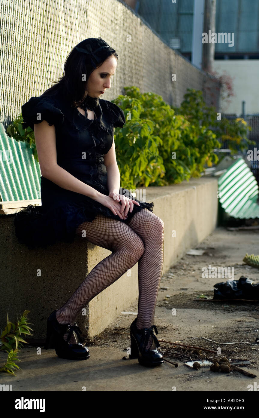 Portrait of a goth girl sitting in an shaded industrial area Stock ...