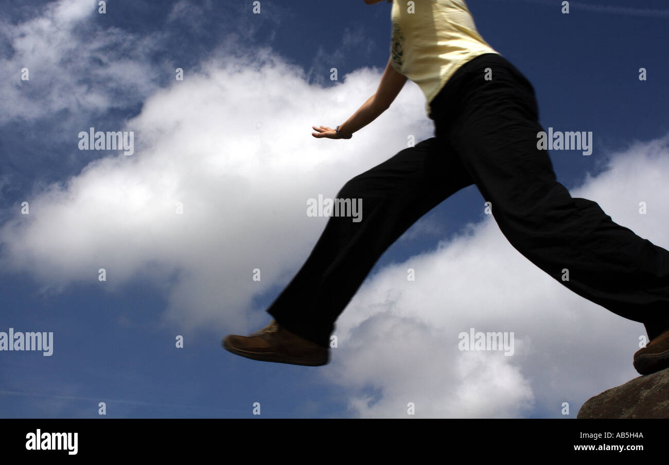 jumping between two rocks with sky and clouds Stock Photo - Alamy
