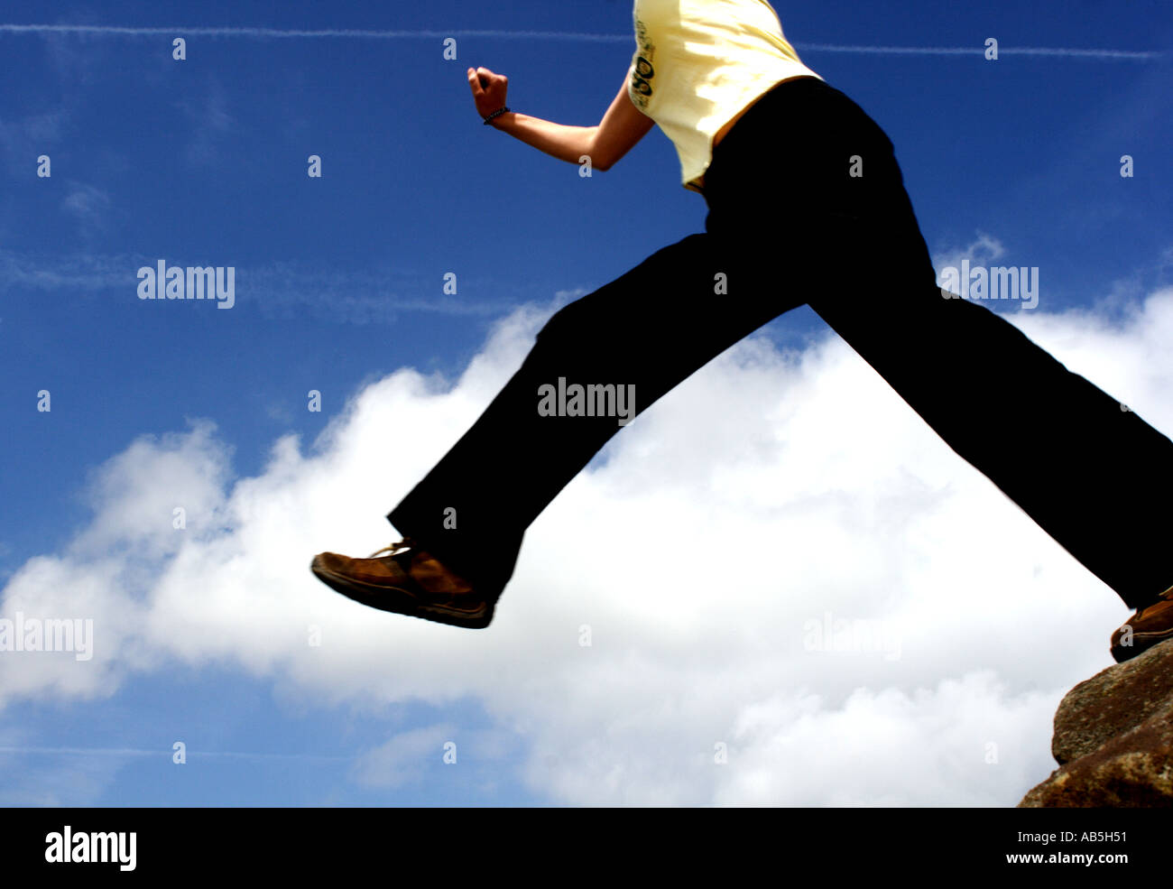 jumping between two rocks with sky and clouds Stock Photo - Alamy