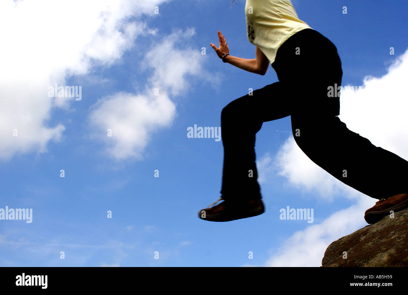 jumping between two rocks with sky and clouds Stock Photo - Alamy