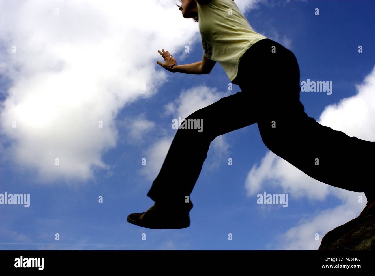 jumping between two rocks with sky and clouds Stock Photo - Alamy