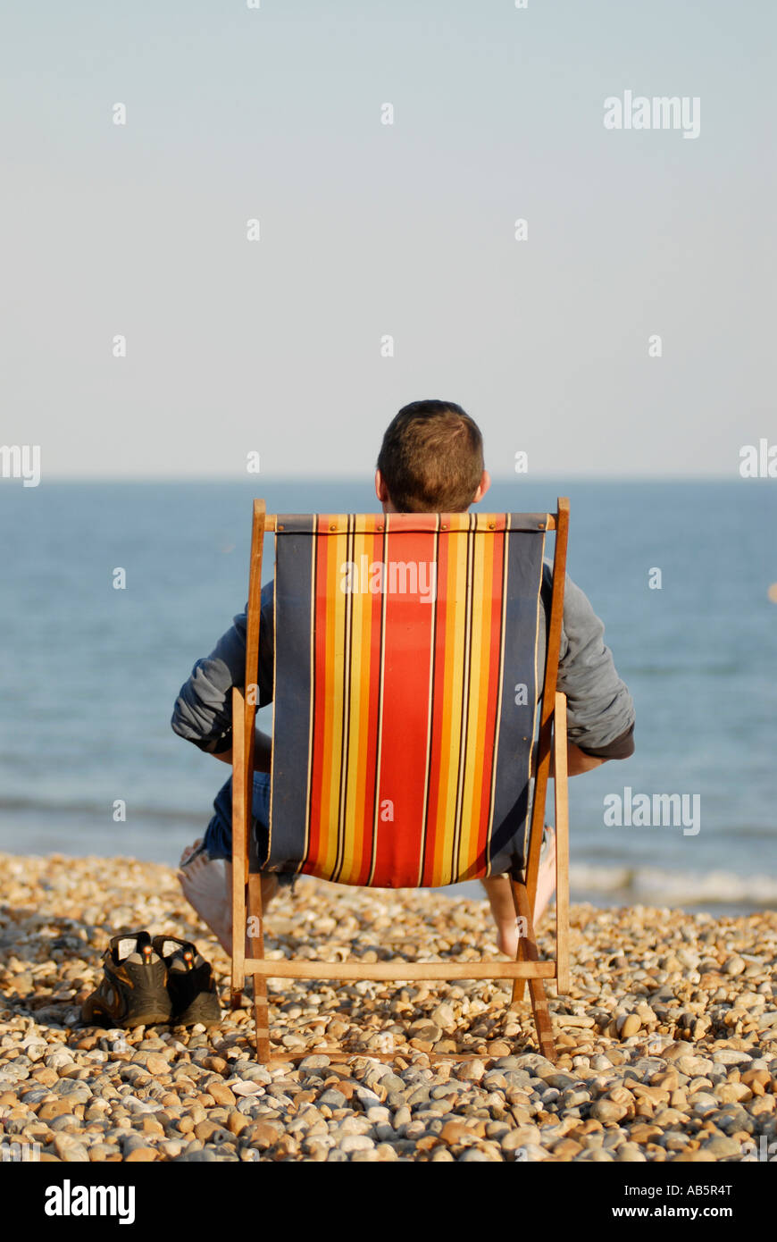 man in deck chair sitting on pebbled beach by the sea Stock Photo - Alamy