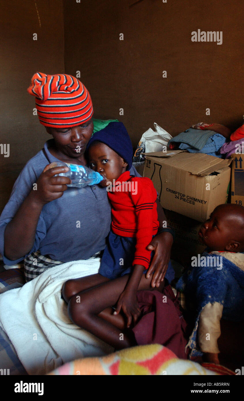 A mother feeds her sick child who is suffering from HIV/AIDS related ...