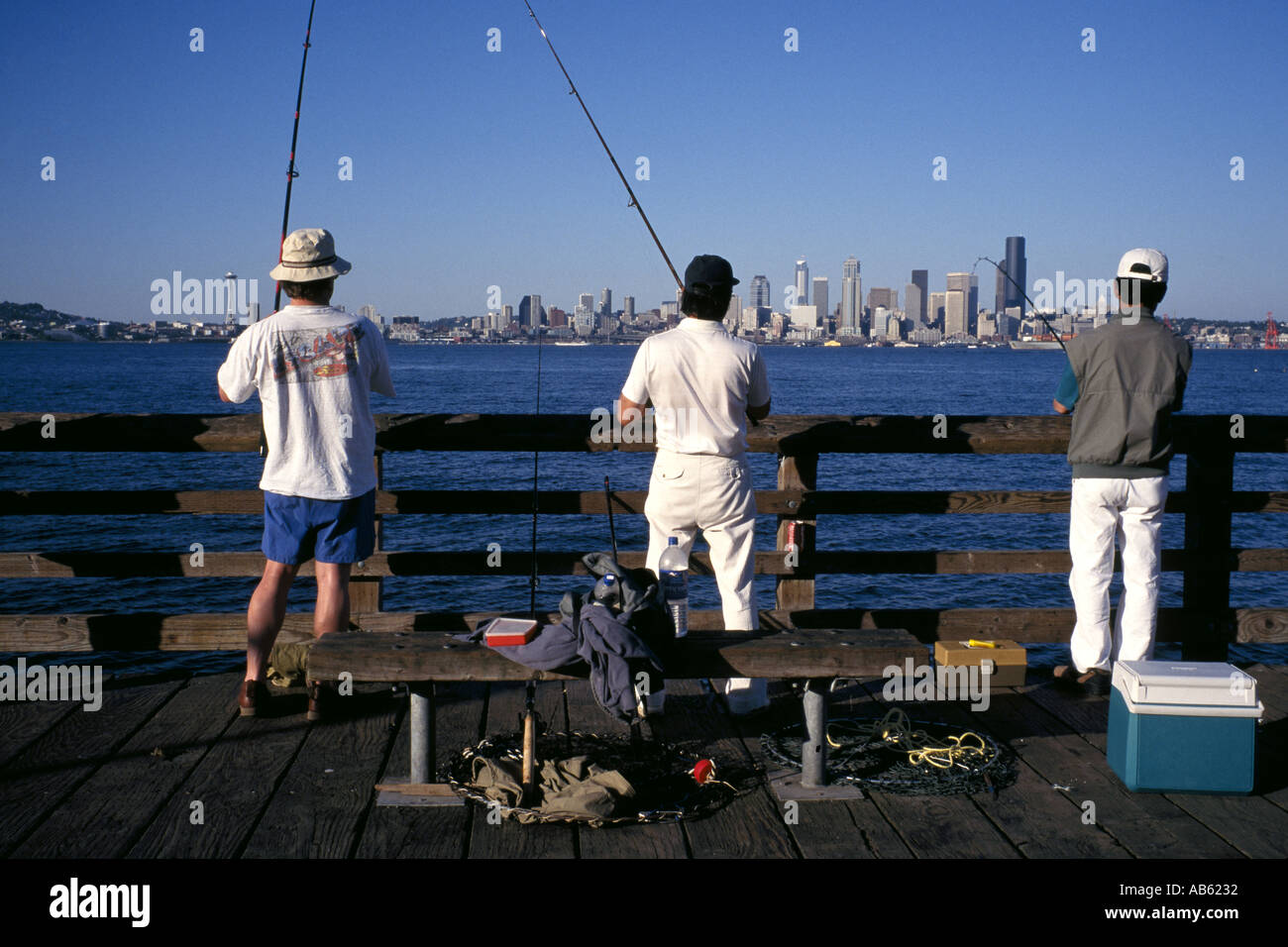 Men fishing from public fishing pier on Elliot Bay at sunset with ...