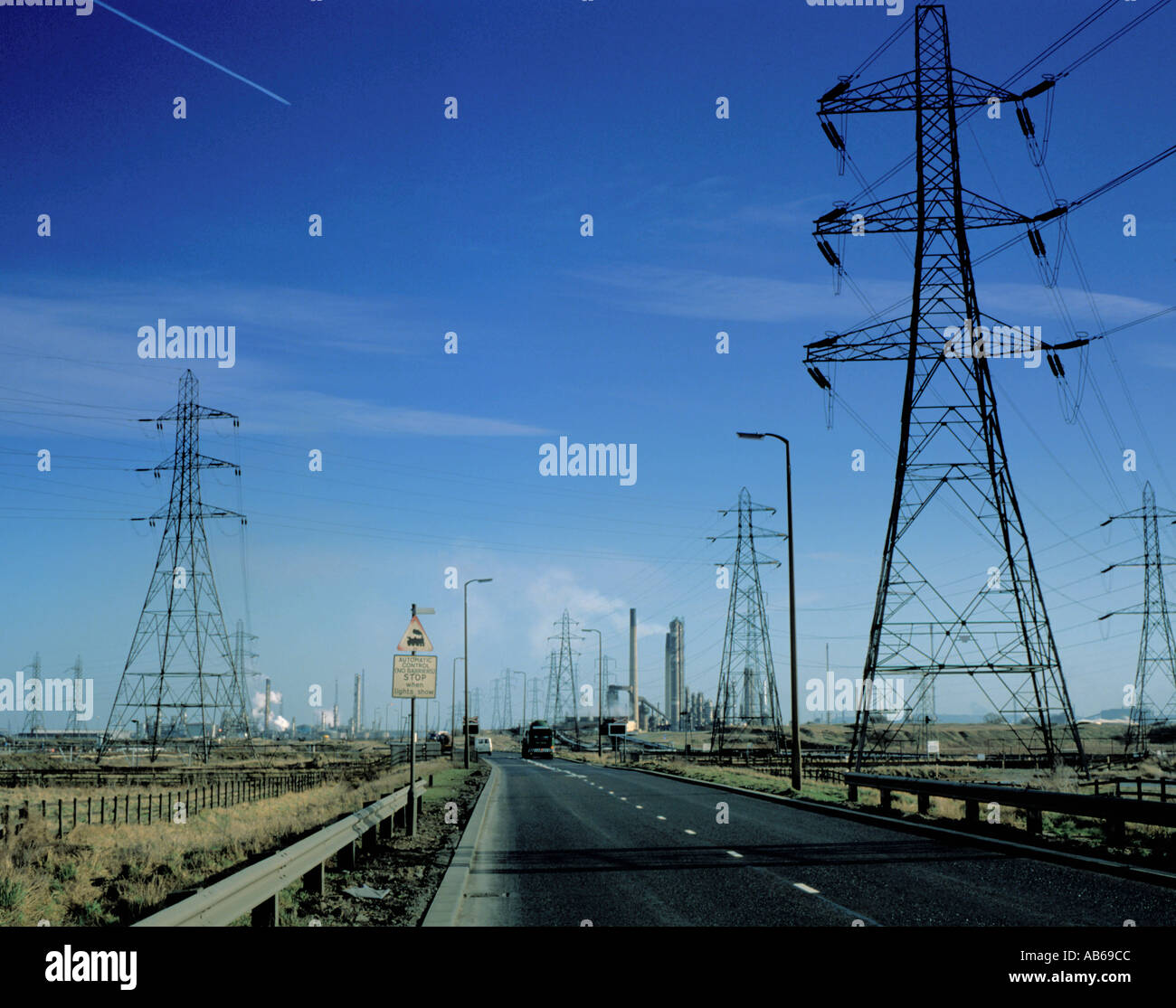 Electricity pylons in an industrial landscape, with road stretching ...
