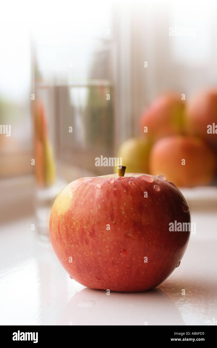 APPLES ON WINDOW SILL WITH ONE APPLE IN FOREGROUND WITH GLASS OF WATER ...
