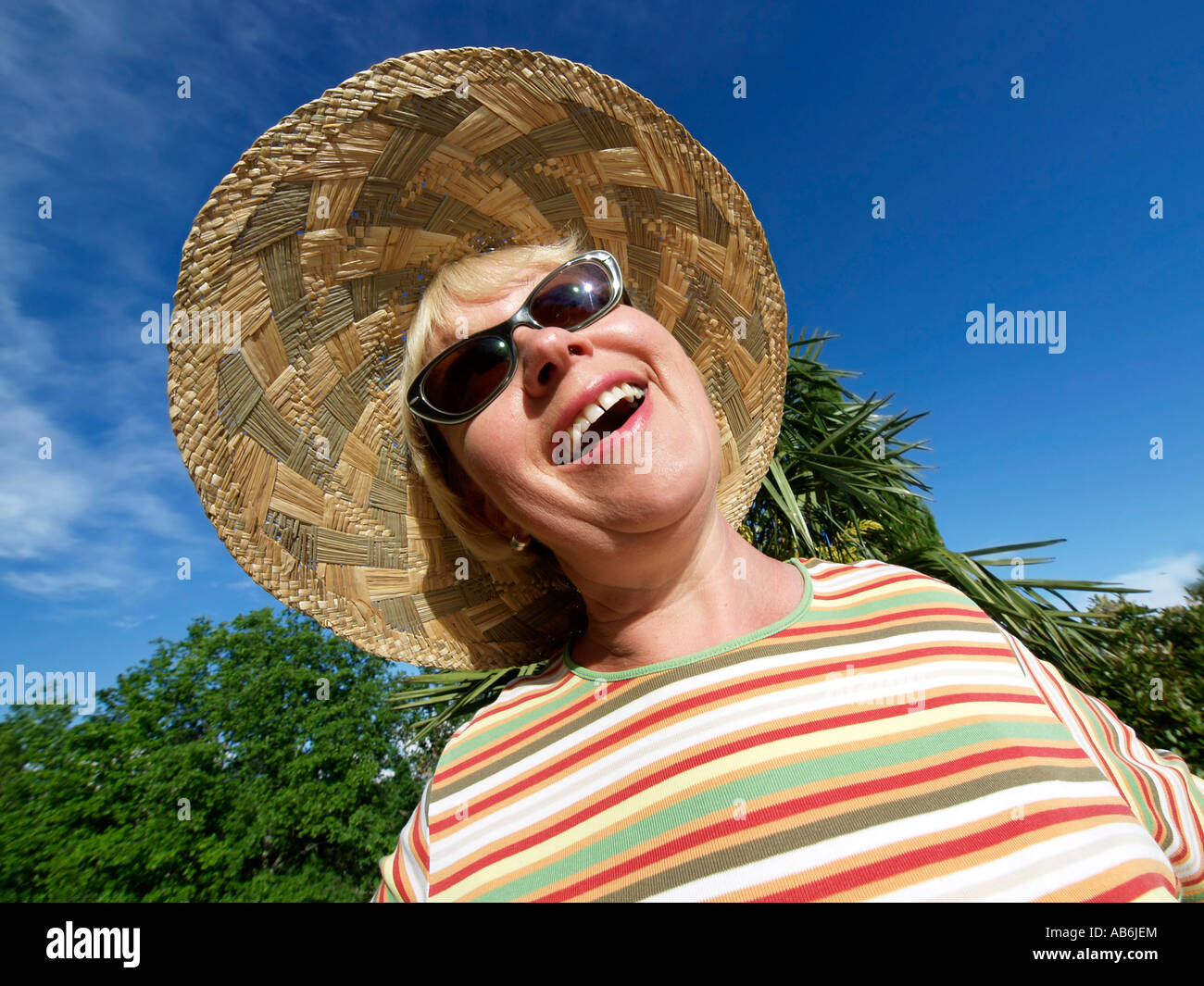 MR middle aged woman with sun hat sunglasses in holiday mood palms in ...