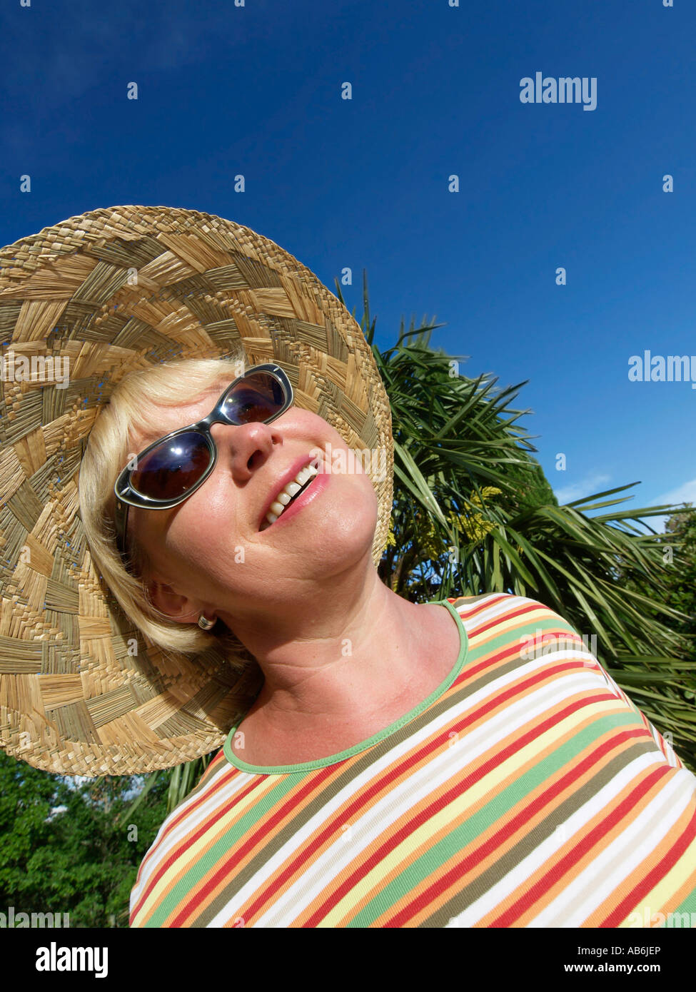 MR middle aged woman with sun hat sunglasses in holiday mood palms in ...