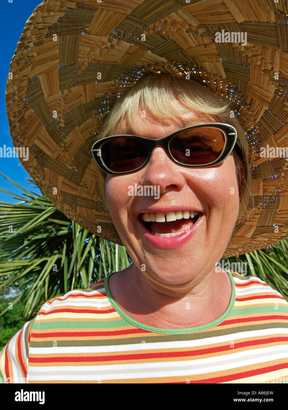 MR middle aged woman with sun hat sunglasses in holiday mood palms in ...