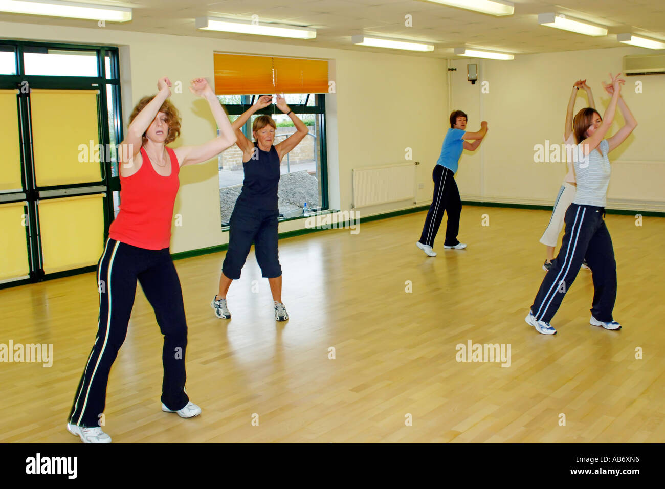 Females doing hip wiggle and clapping exercises in a workout class ...