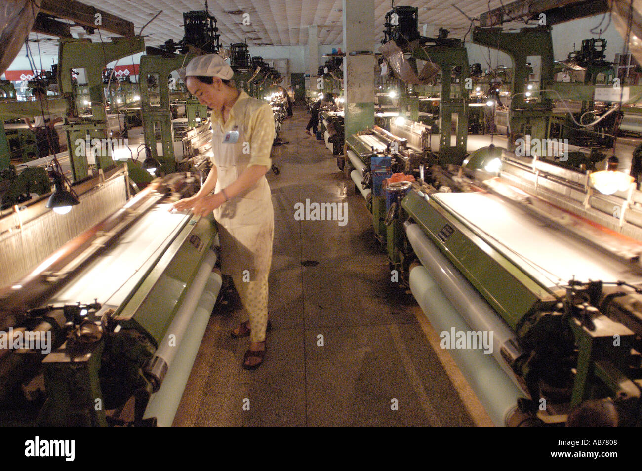 A female worker inspects machines in a traditional silk thread factory ...